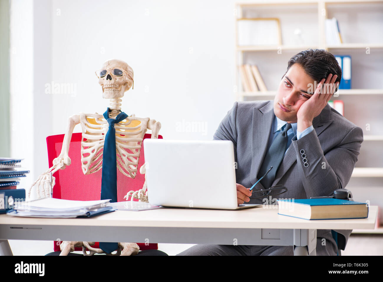 Businessman working with skeleton in office Stock Photo - Alamy
