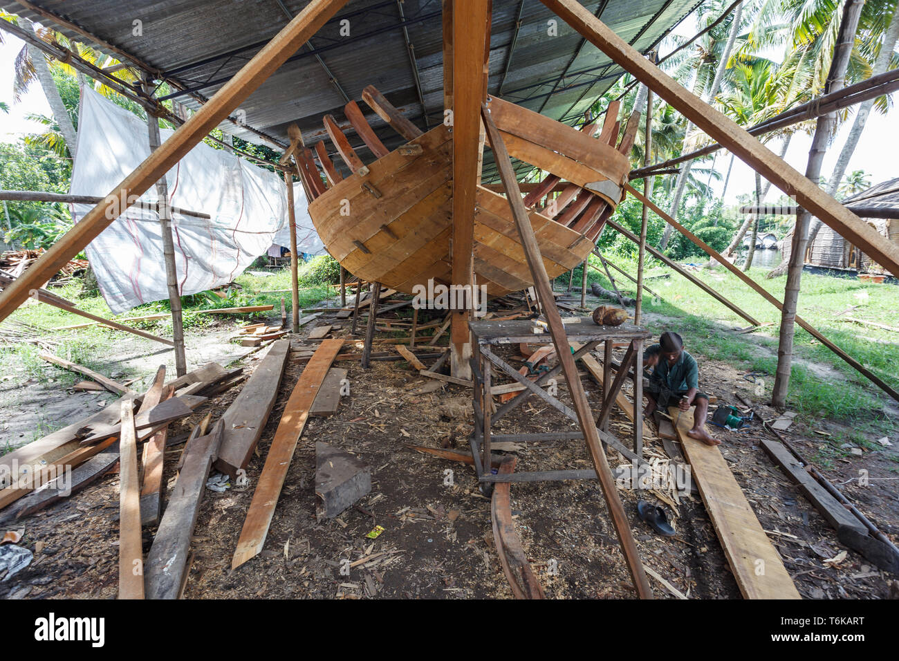 Closeup of a man working on construction of a traditional fishing boat ...