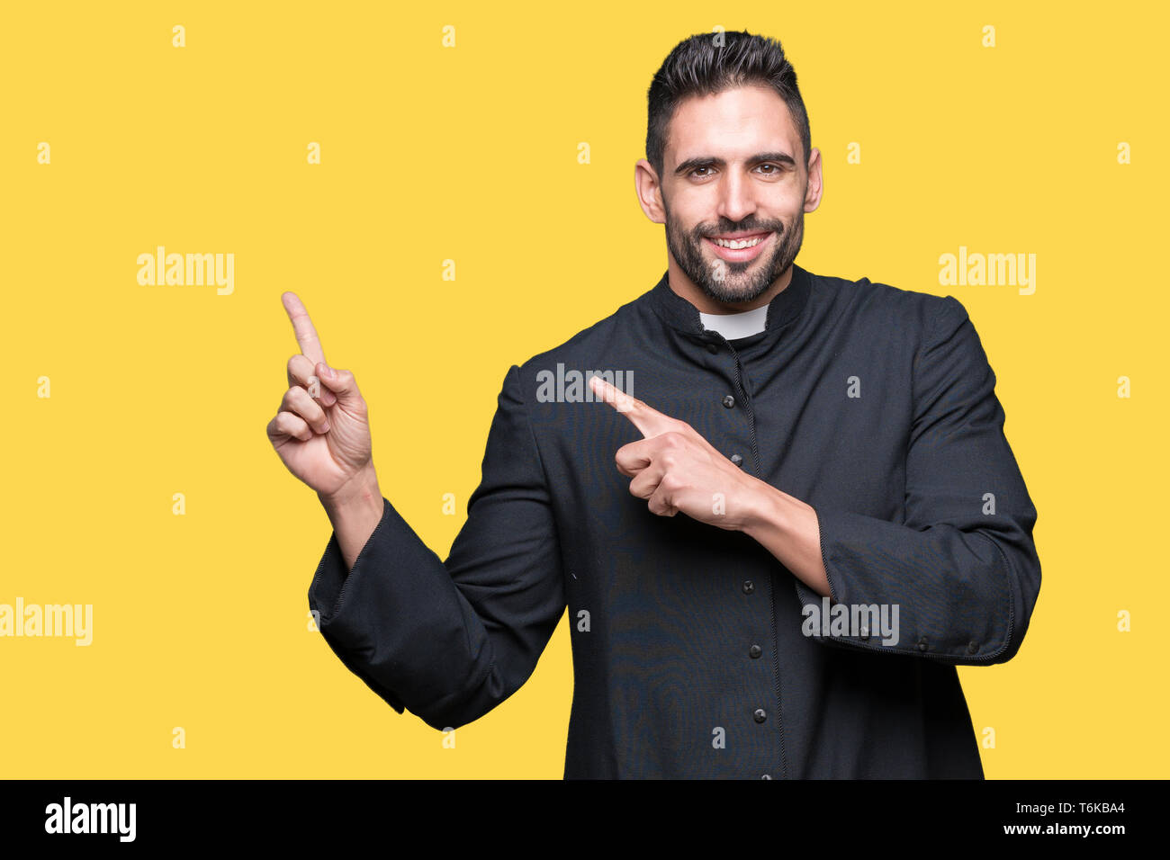 Young Christian priest over isolated background smiling and looking at ...