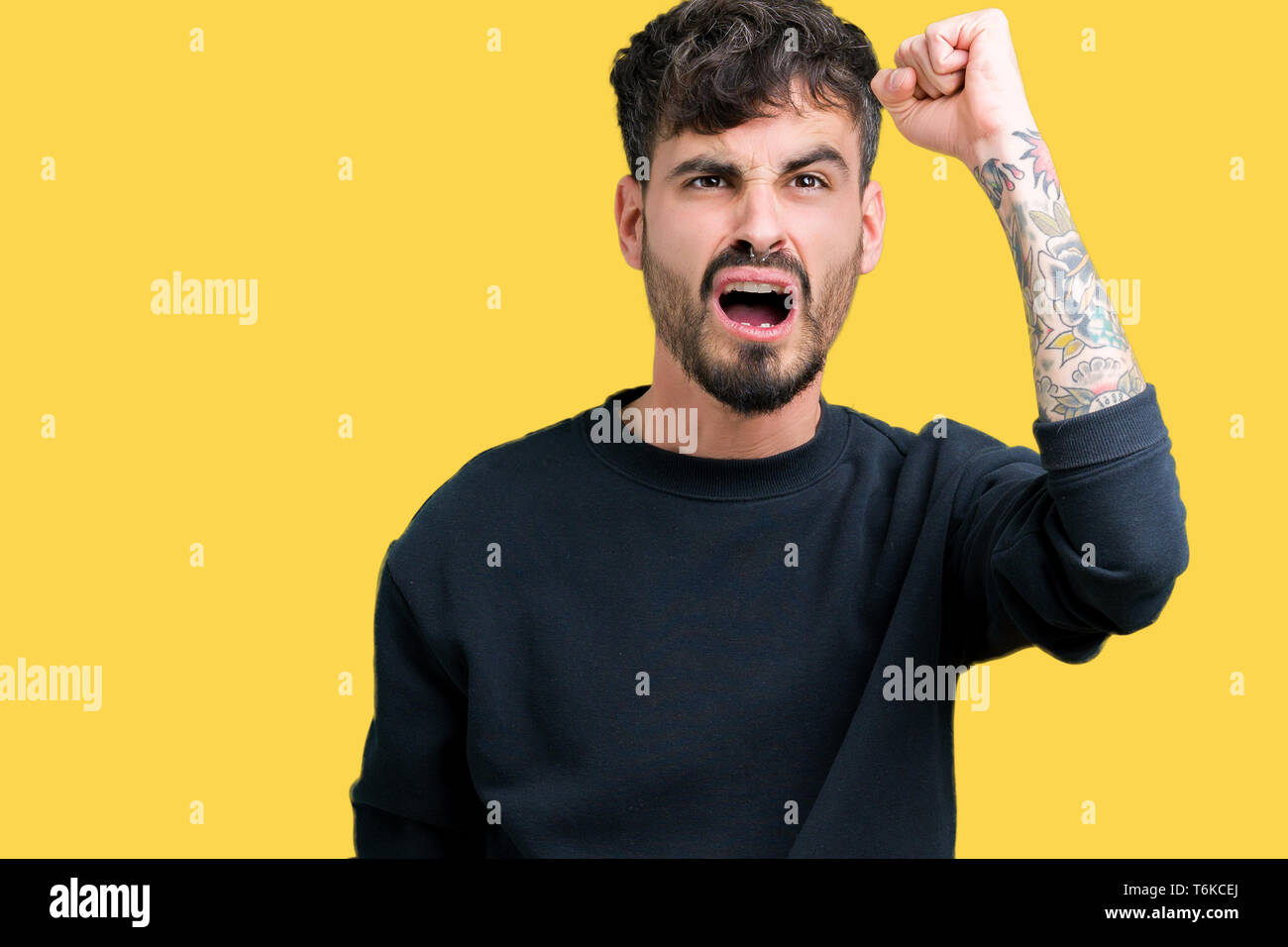 Young handsome man over isolated background angry and mad raising fist ...