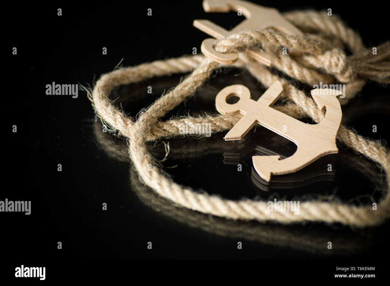 wooden decorative anchor with rope on black Stock Photo - Alamy