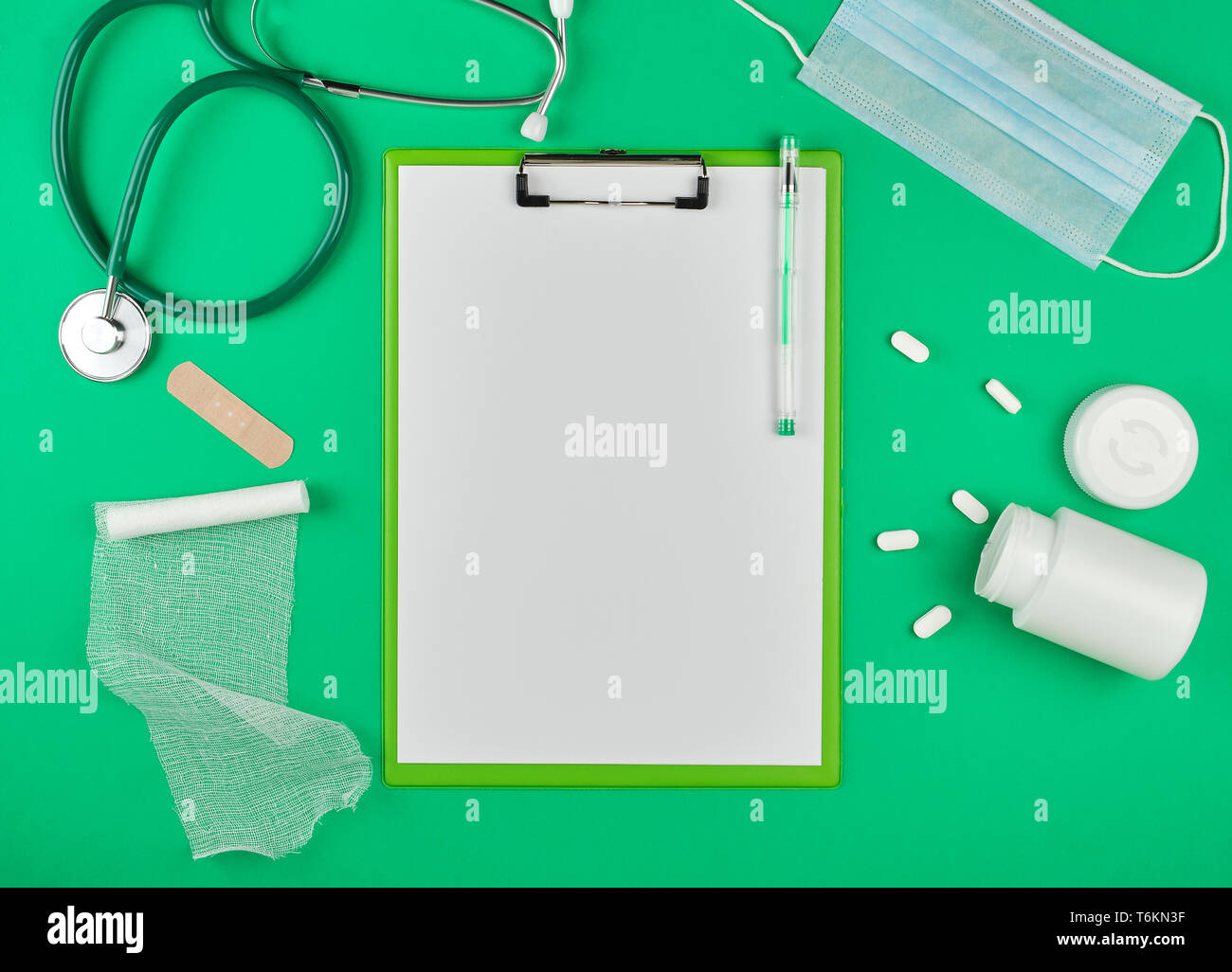 paper holder with empty white sheets, medical stethoscope, pills on a ...