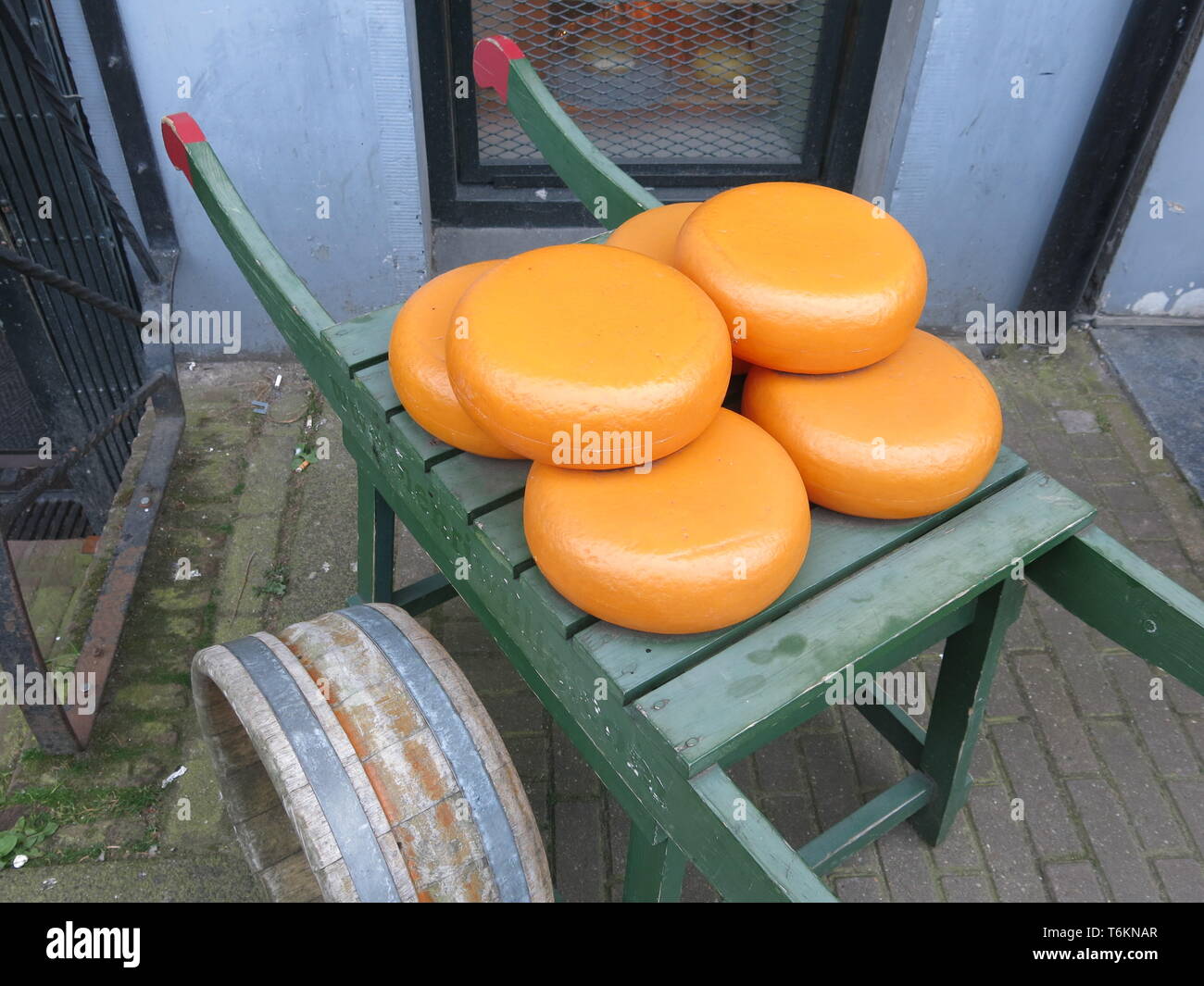 A traditional green wheel cart carrying six round, flat, Dutch cheeses ...