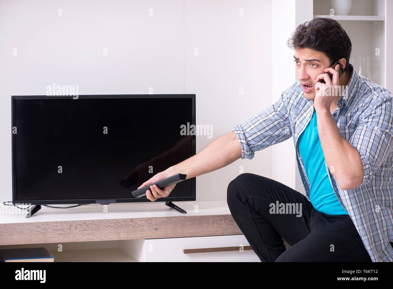 Man trying to fix broken tv Stock Photo - Alamy