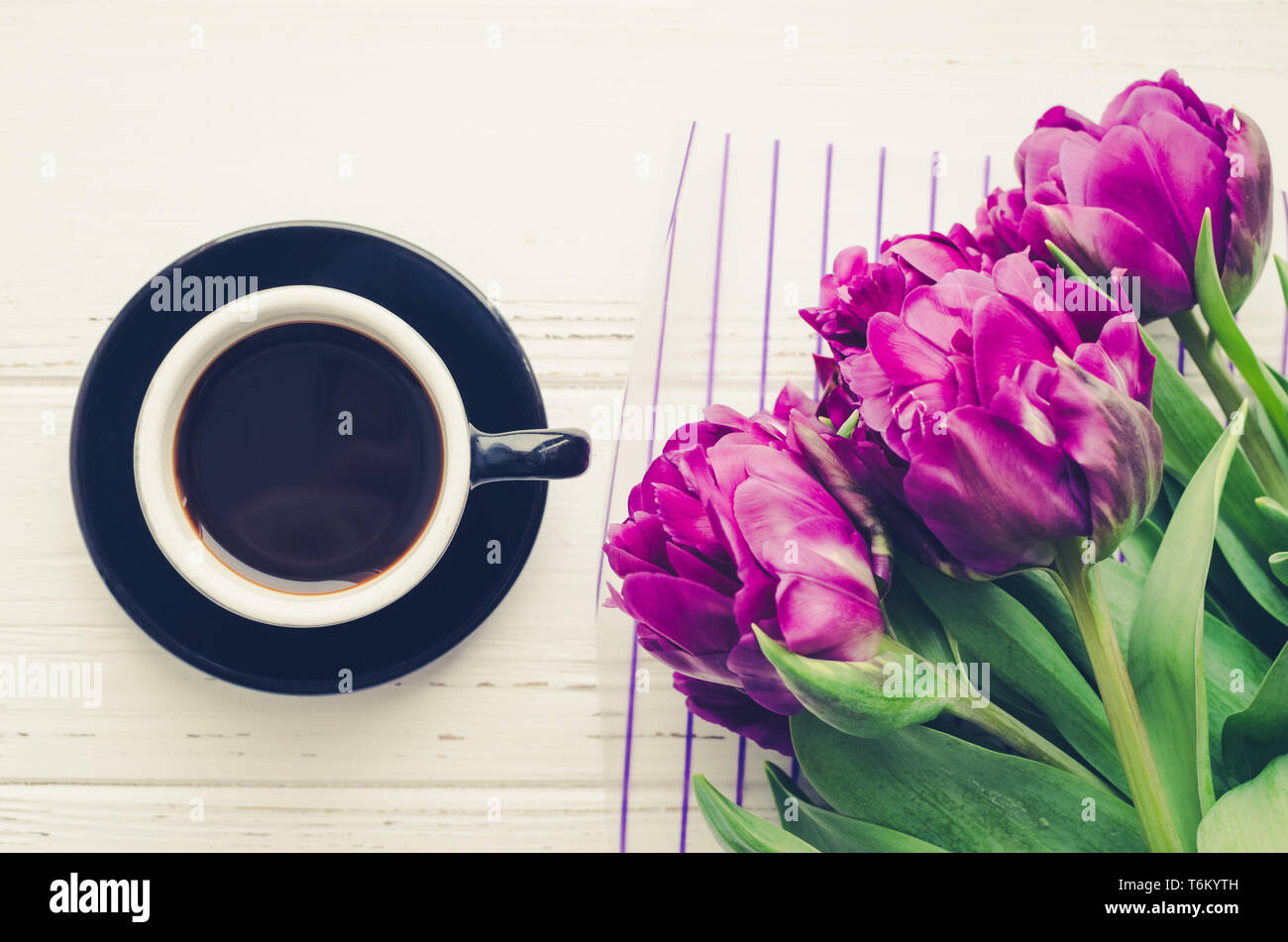 Cup of morning coffee and bouquet of spring flowers tulips over white ...