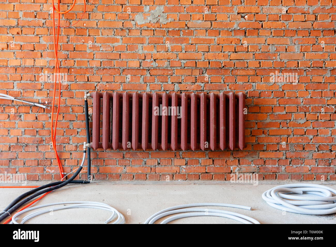 Radiator and bundles of corrugated pipes against a brick wall. Interior ...