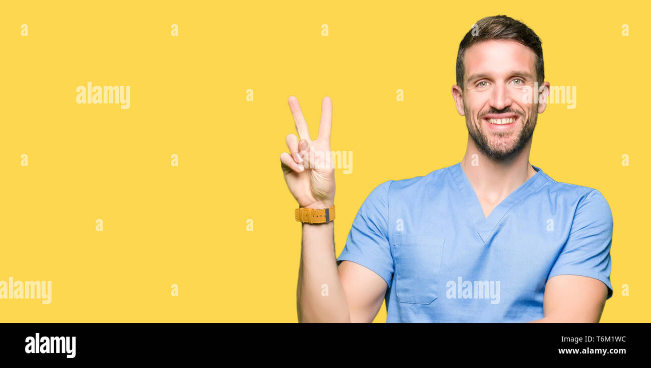 Handsome doctor man wearing medical uniform over isolated background ...