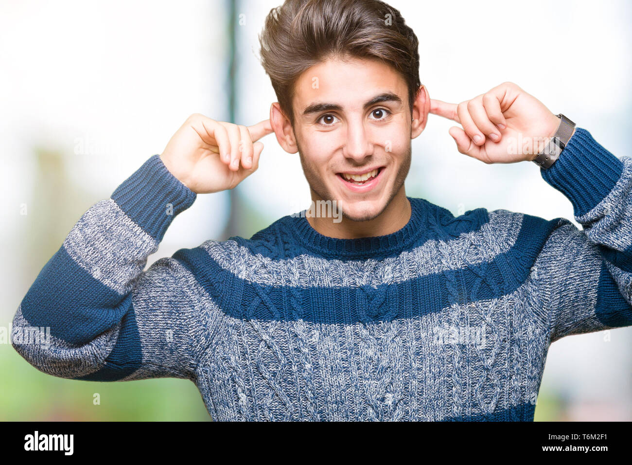 Young handsome man over isolated background Smiling pulling ears with ...