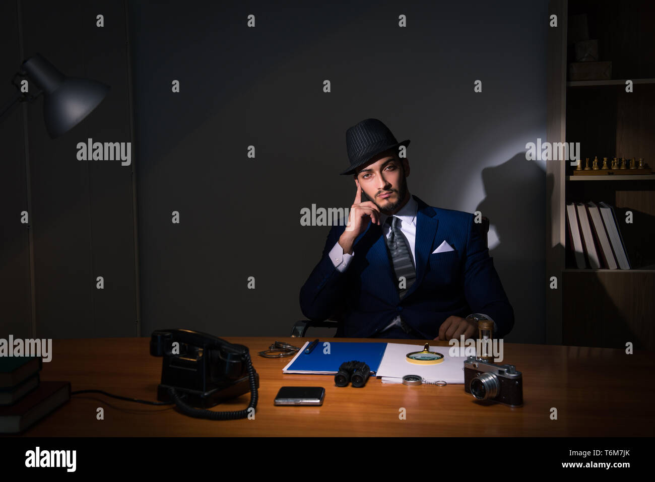 Detective sitting in dark room in vintage concept Stock Photo - Alamy