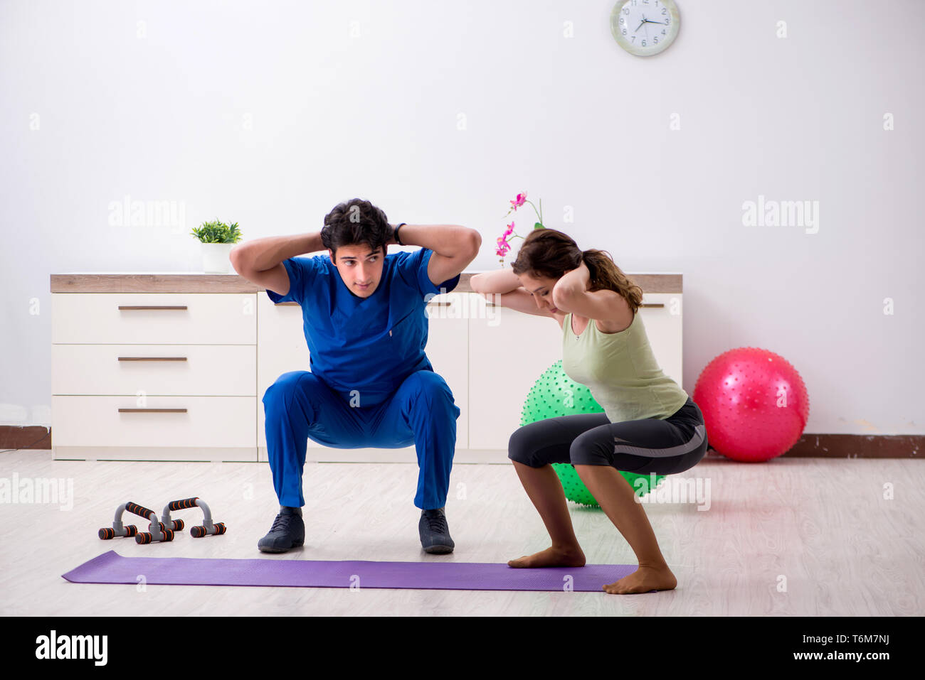 Fitness instructor helping sportsman during exercise Stock Photo - Alamy