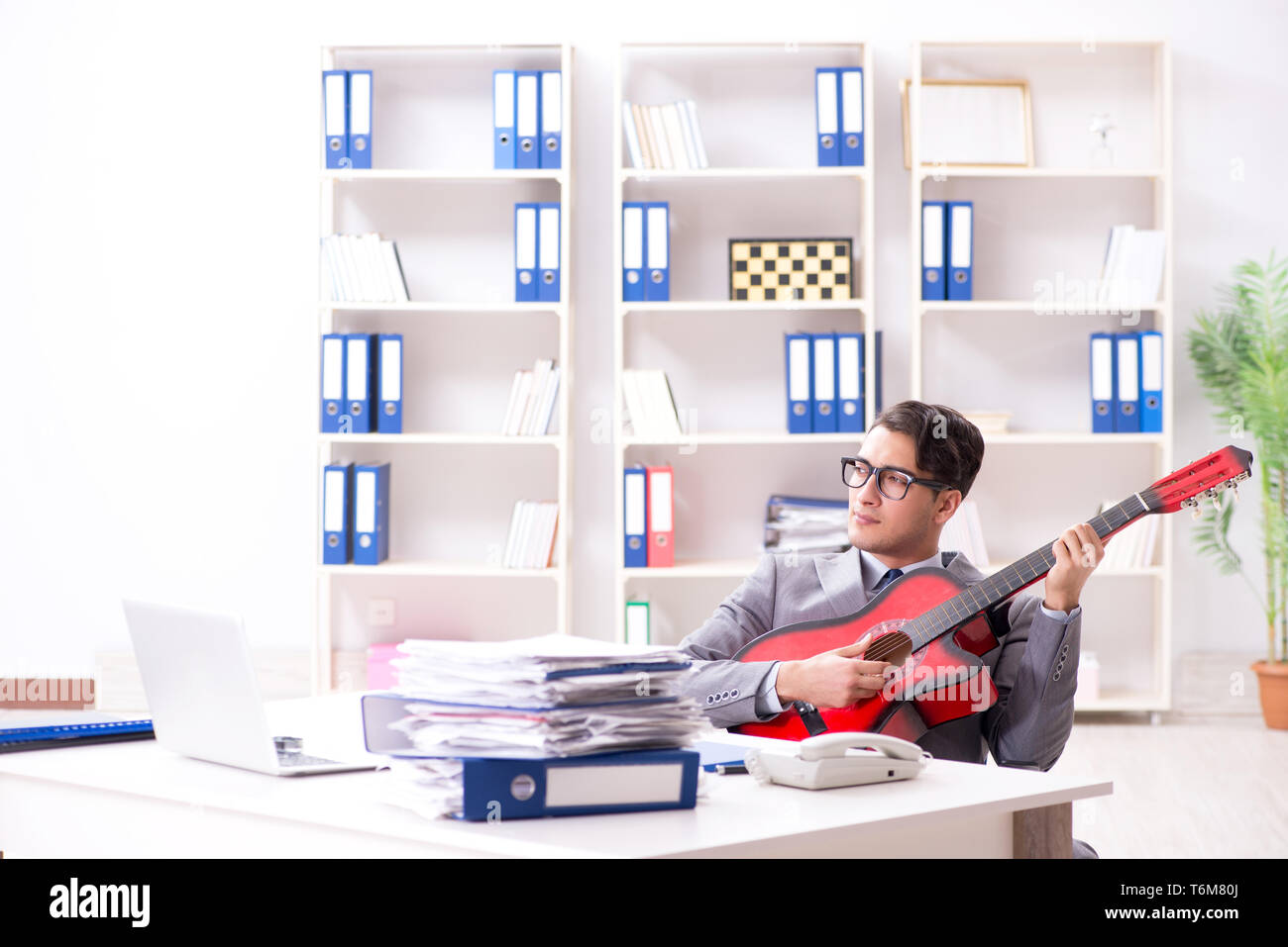 Young handsome businessman playing guitar in the office Stock Photo - Alamy