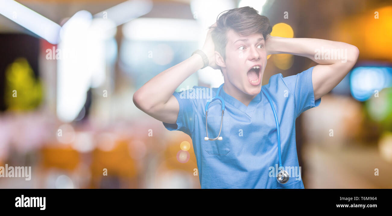 Young doctor wearing medical uniform over isolated background Crazy and ...
