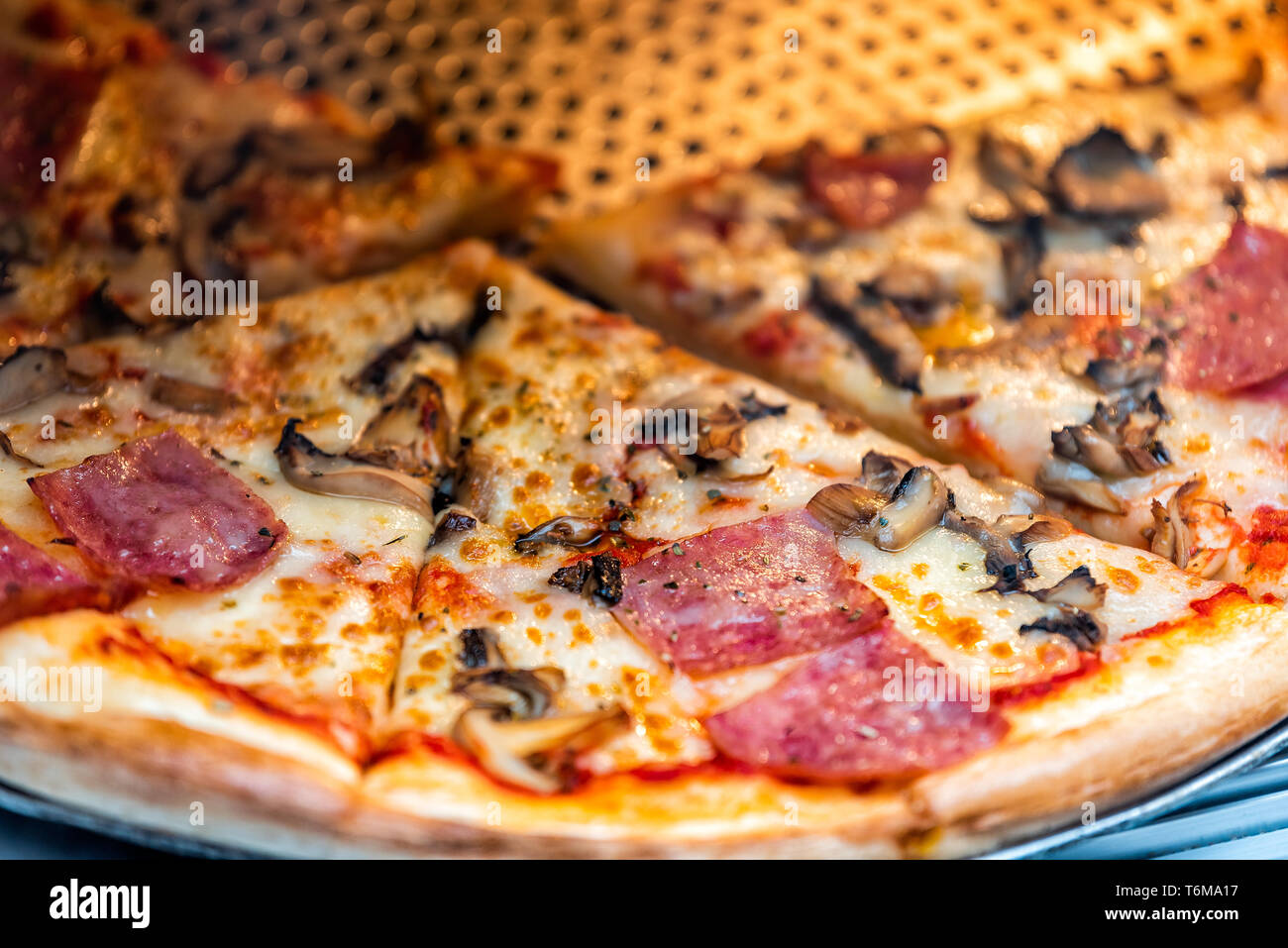Macro closeup of fresh thin crust round pizza in store cafe on display ...