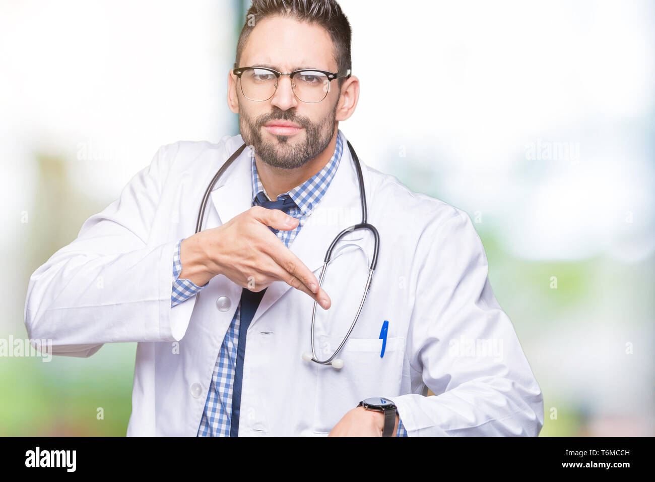 Handsome young doctor man over isolated background In hurry pointing to ...