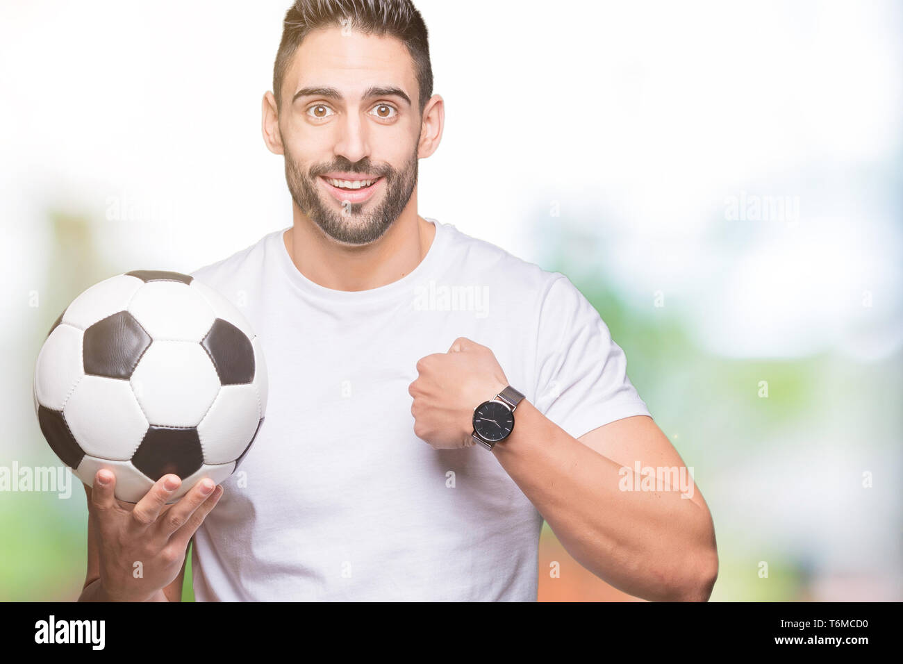 Young man holding soccer football ball over isolated background with ...