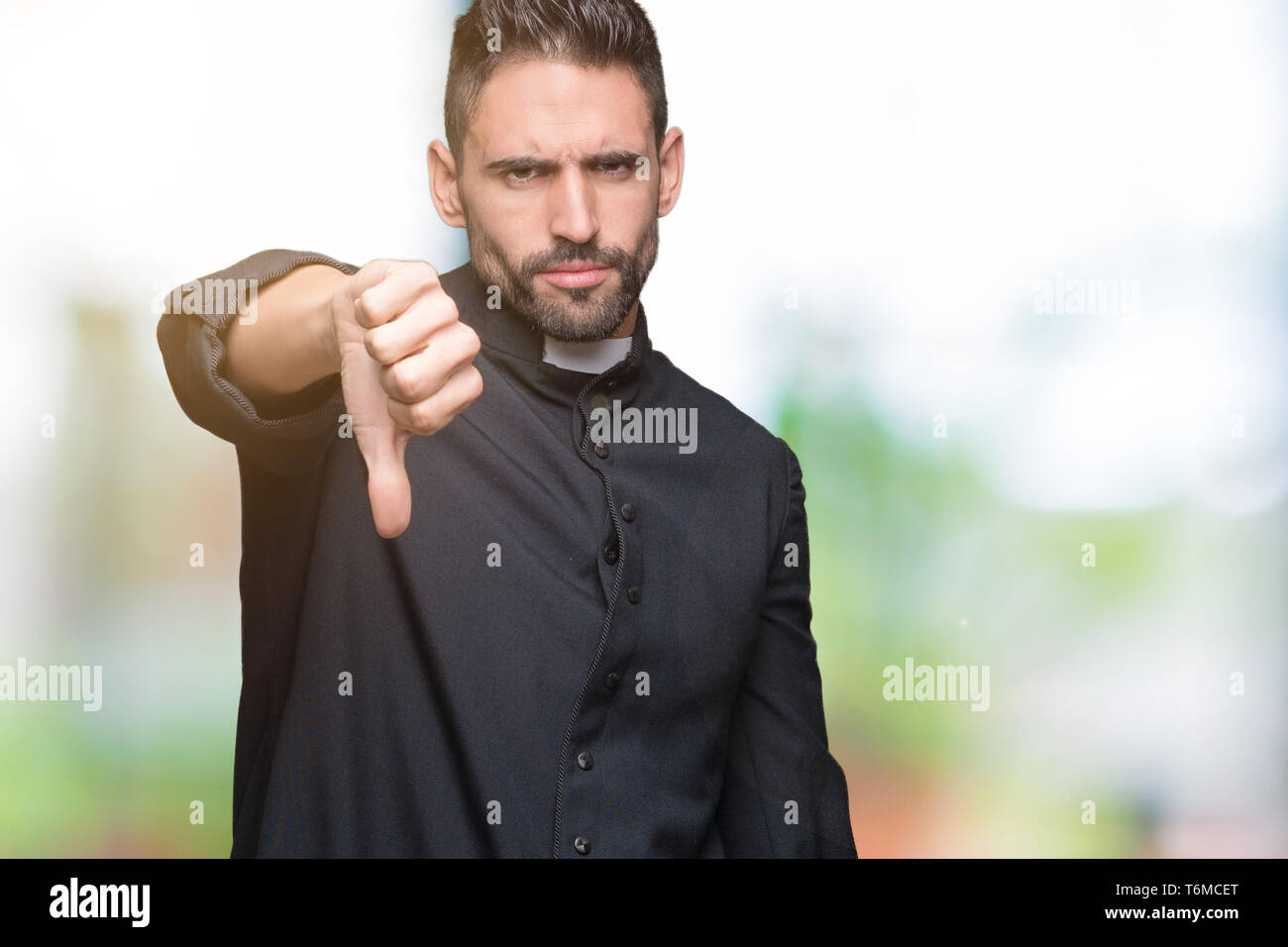 Young Christian priest over isolated background looking unhappy and ...