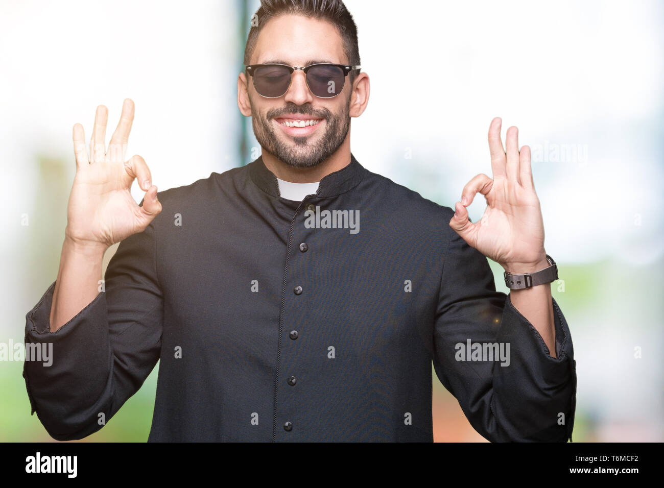 Young Christian priest wearing sunglasses over isolated background ...