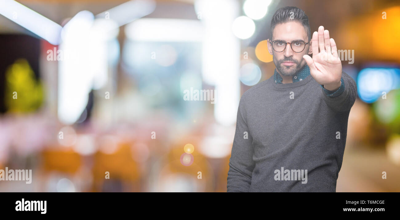 Young handsome man wearing glasses over isolated background doing stop ...