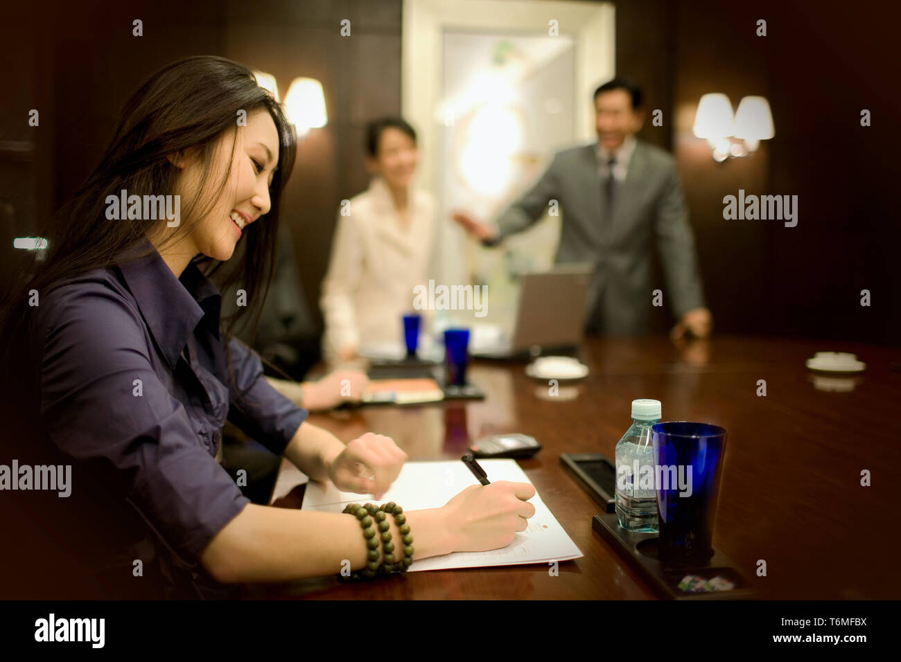 Young adult business woman taking notes for a meeting in a boardroom ...