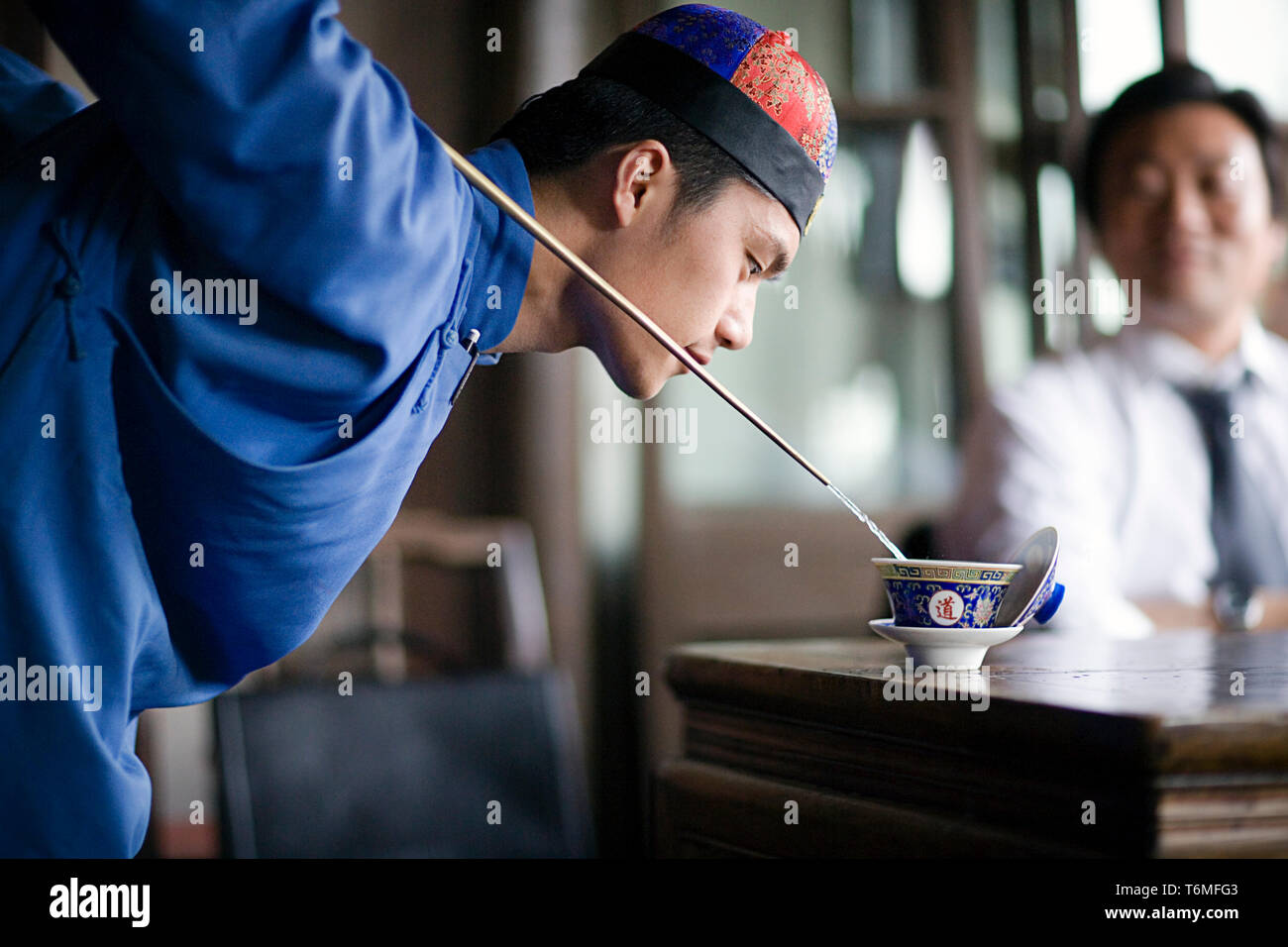 Young adult man dressed in traditional clothing doing a tea ritual in a ...