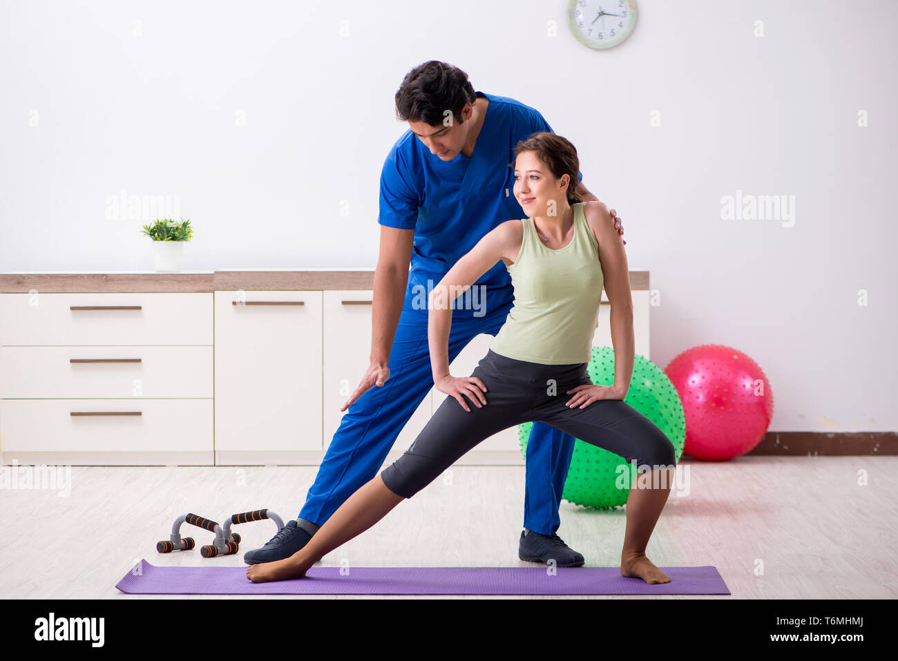 Fitness instructor helping sportsman during exercise Stock Photo - Alamy