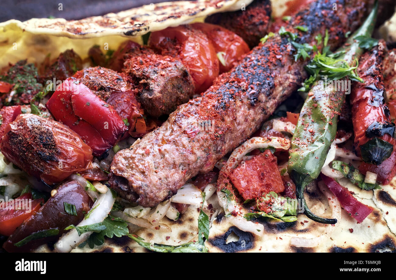 Traditional Adana Kebap with tomato and salad on a flatbread as close ...