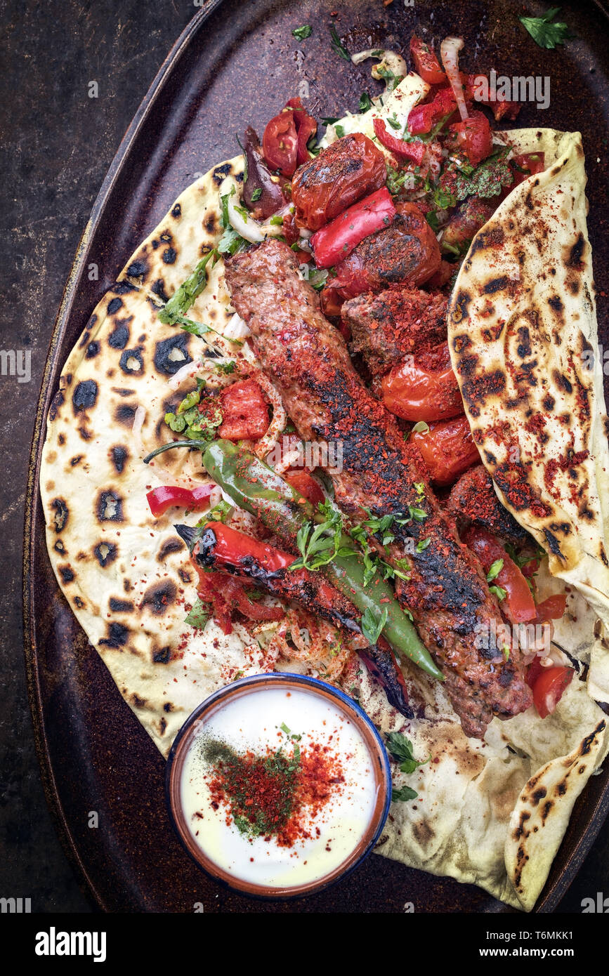 Traditional Adana Kebap with tomato and salad on a flatbread on a plate ...