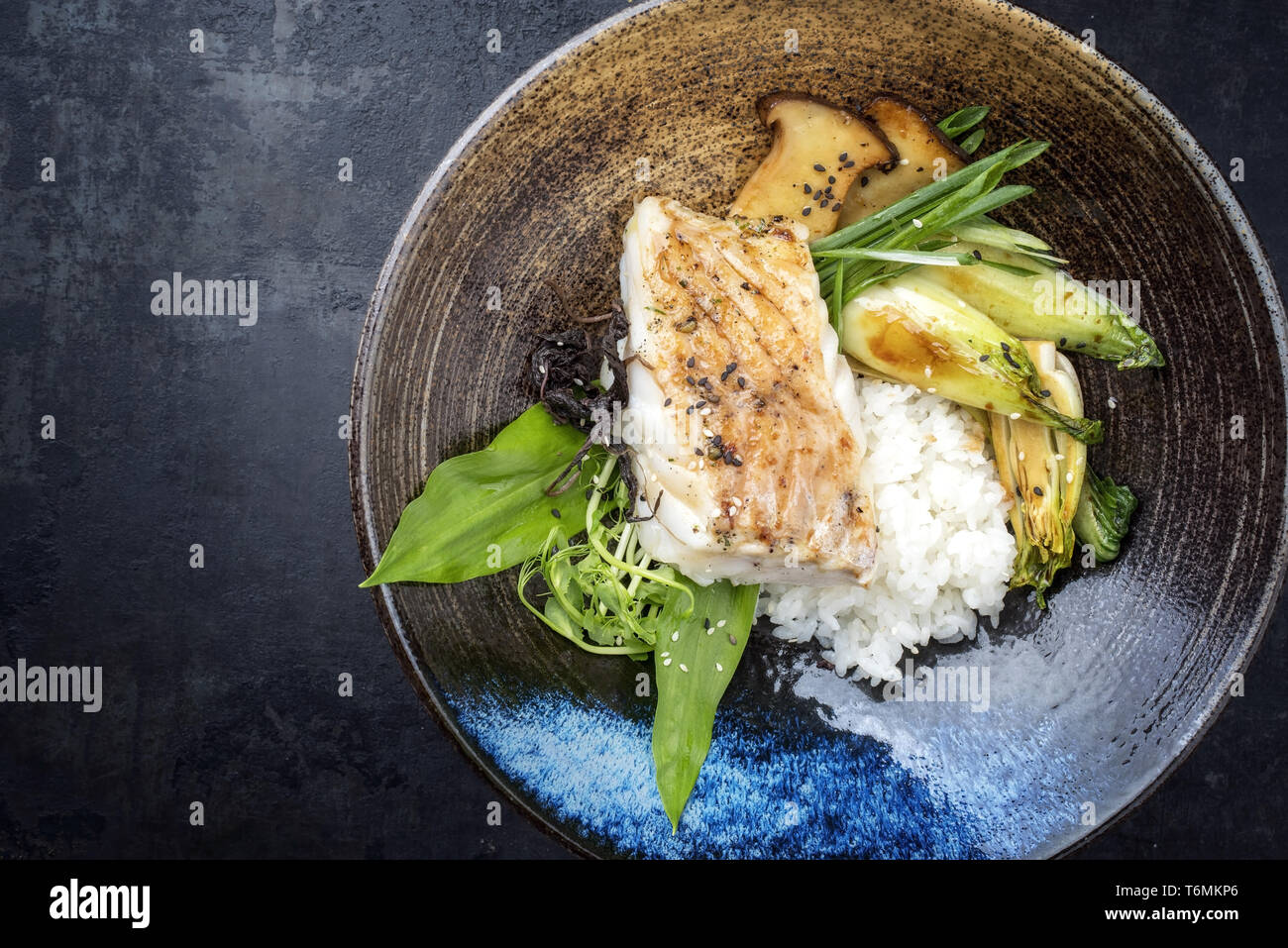 Modern Japanese fried cod fish filet with bok choi and rice as top view ...
