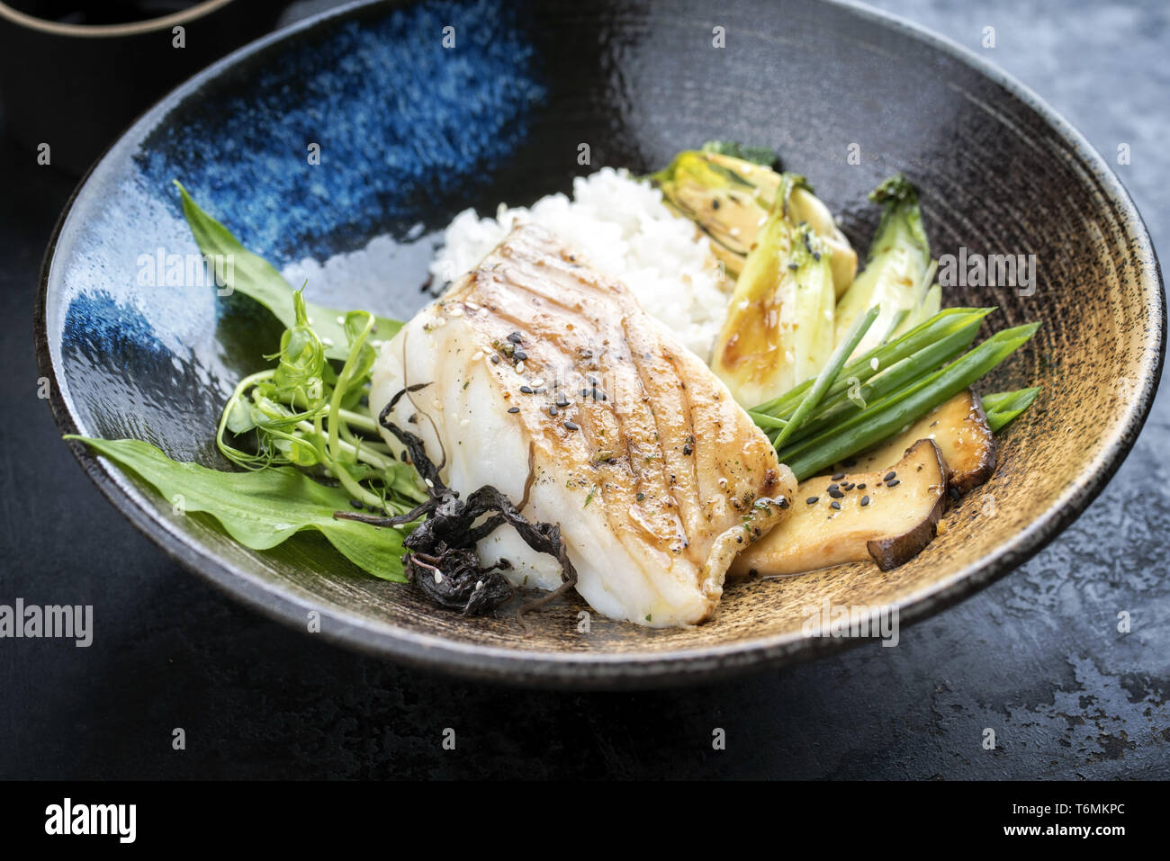 Modern Japanese fried cod fish filet with bok choi and rice as top view ...