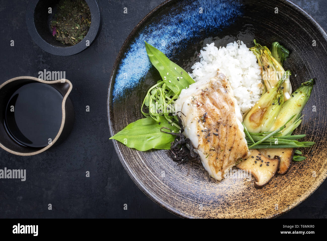 Modern Japanese fried cod fish filet with bok choi and rice as top view ...