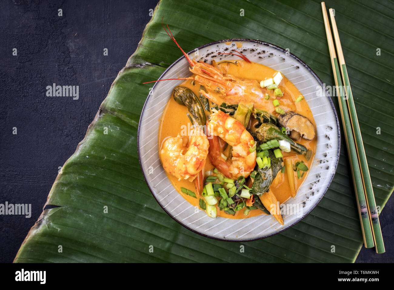Traditional Thai kaeng phet red curry with king prawns and galgant as ...