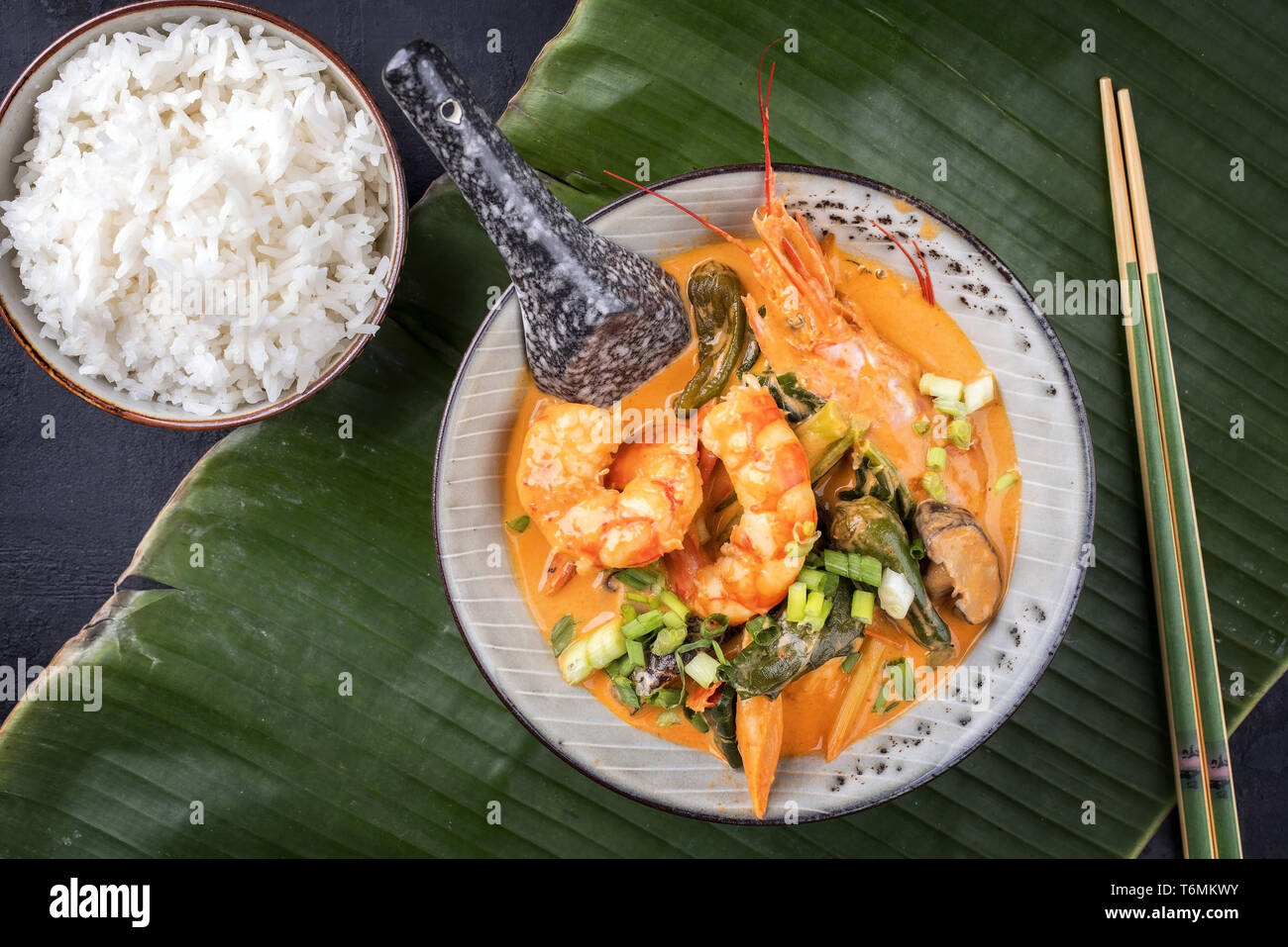 Traditional Thai kaeng phet red curry with king prawns and rice as top ...