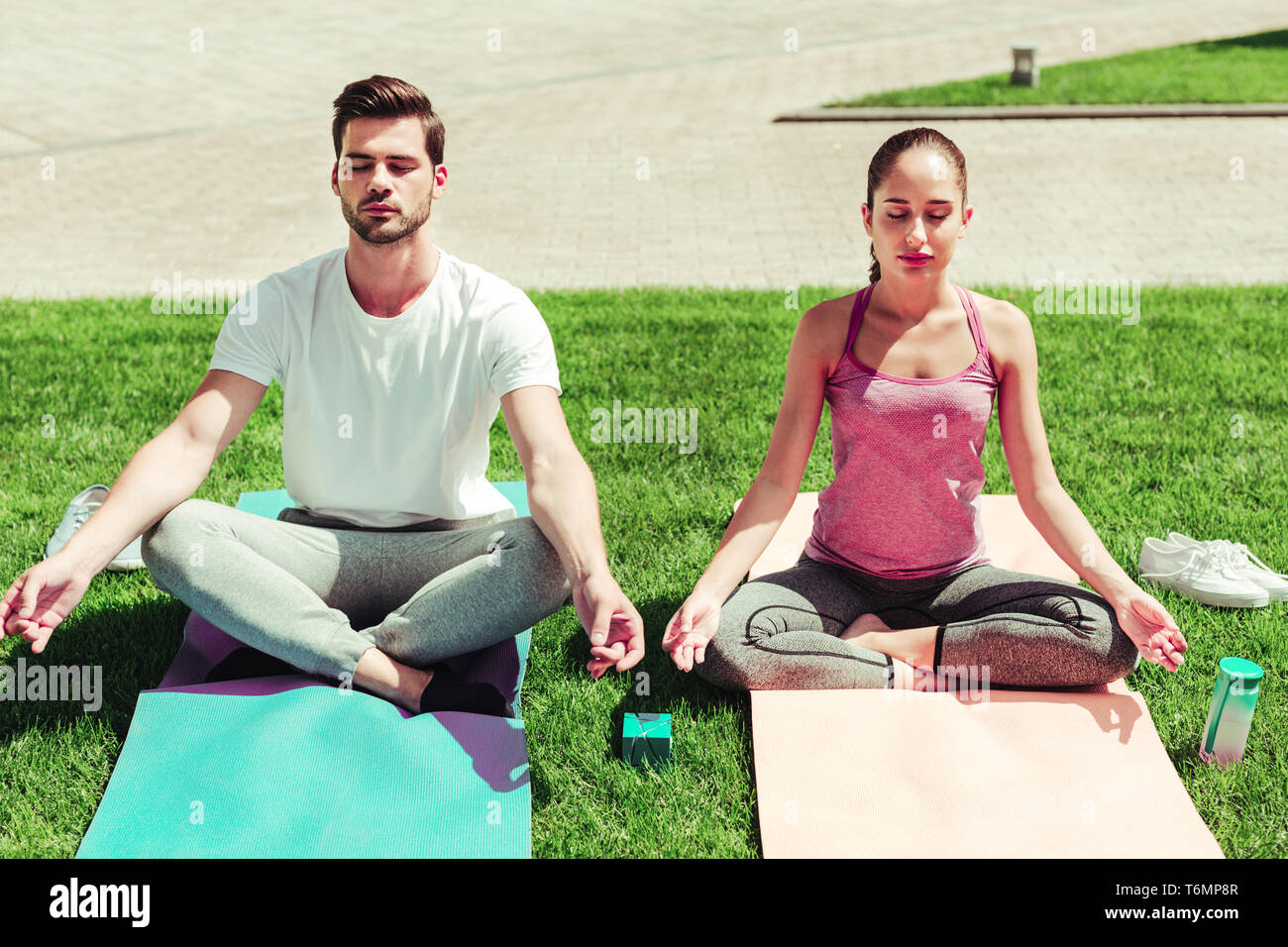 Relaxed young people meditating together in park Stock Photo - Alamy