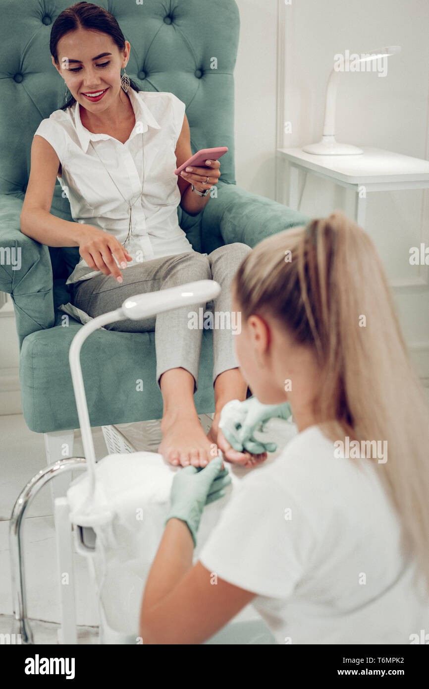 Smiling attentive woman in white shirt observing skills of blonde ...