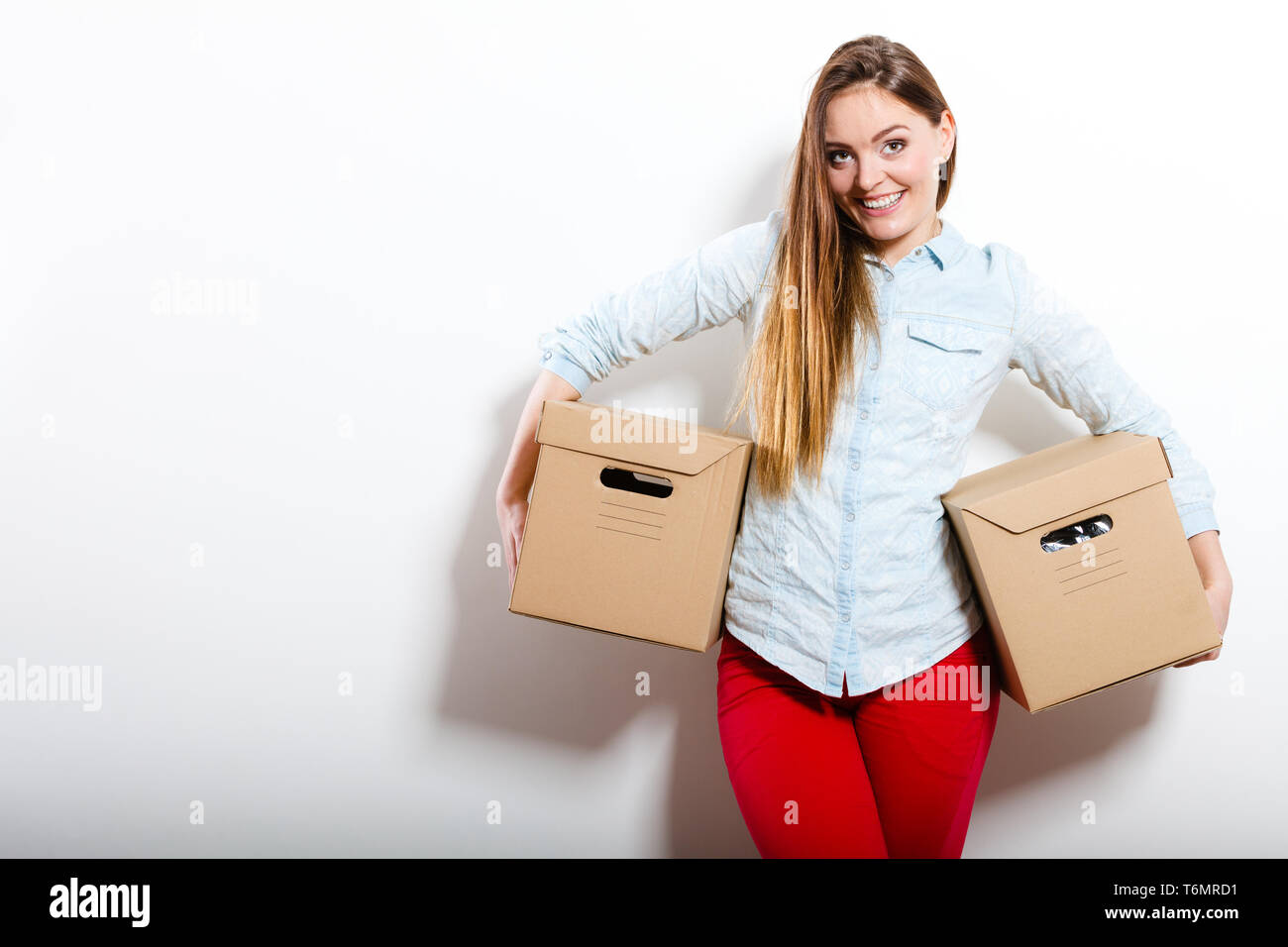 Happy woman moving in carrying cartons boxes. Young girl arranging ...
