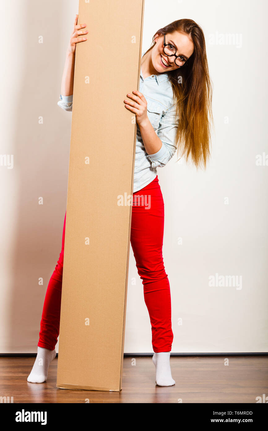 Happy woman moving into new apartment house carrying carton box with ...