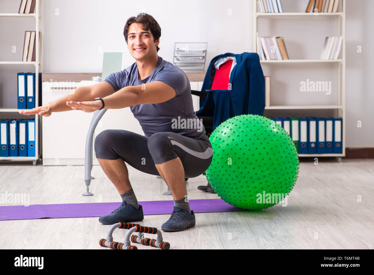 Young male employee exercising in the office Stock Photo - Alamy