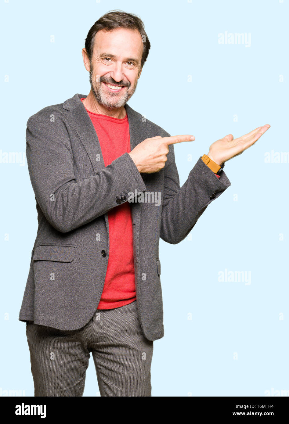 Middle age handsome business man amazed and smiling to the camera while ...