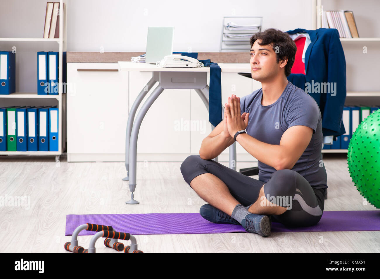 Young male employee exercising in the office Stock Photo - Alamy