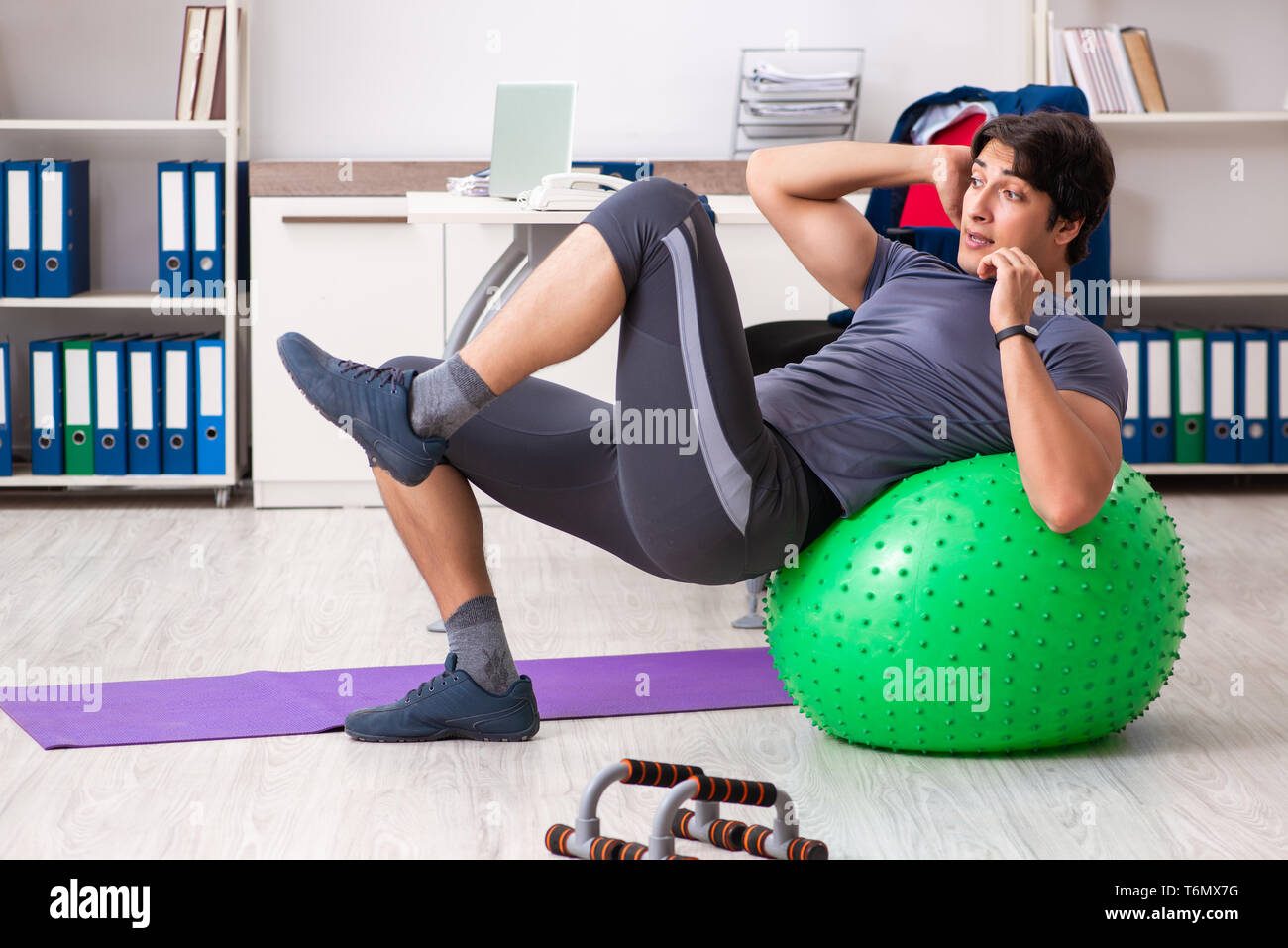 Young male employee exercising in the office Stock Photo - Alamy