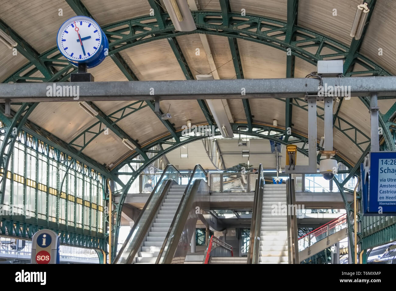 Railway station concourse with escalators, information panel and clock ...