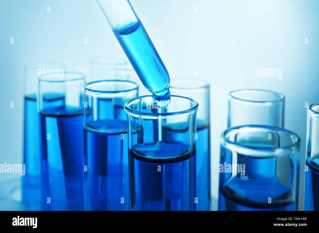 Dripping blue liquid into test tubes on color background Stock Photo ...