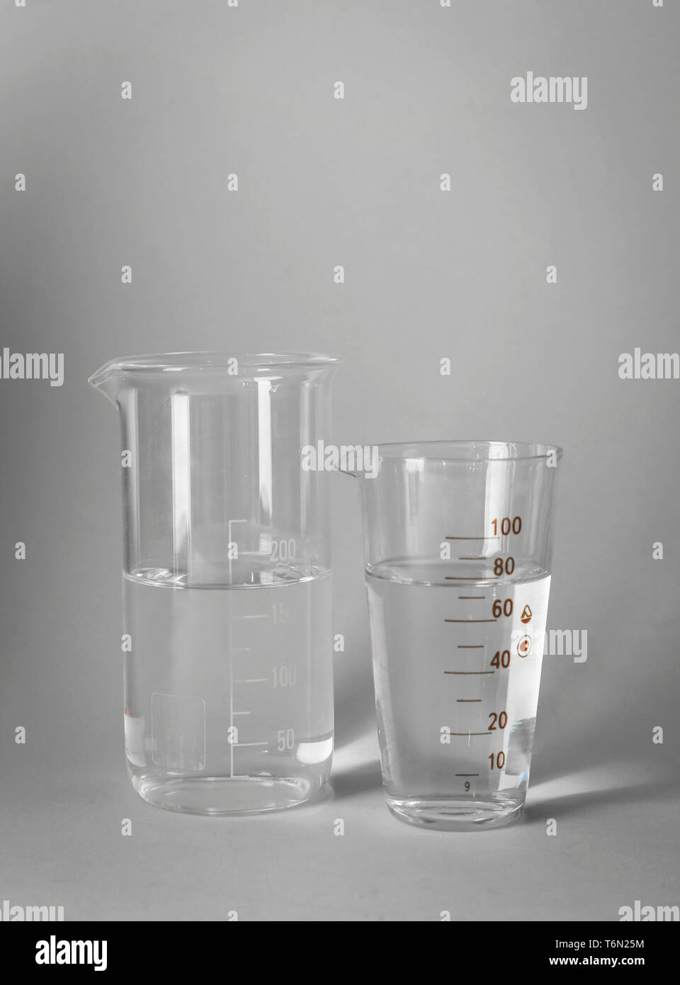 Glass beakers with water on light background Stock Photo - Alamy