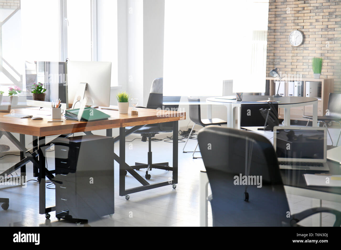 Office interior with tables and armchairs, view through glass ...