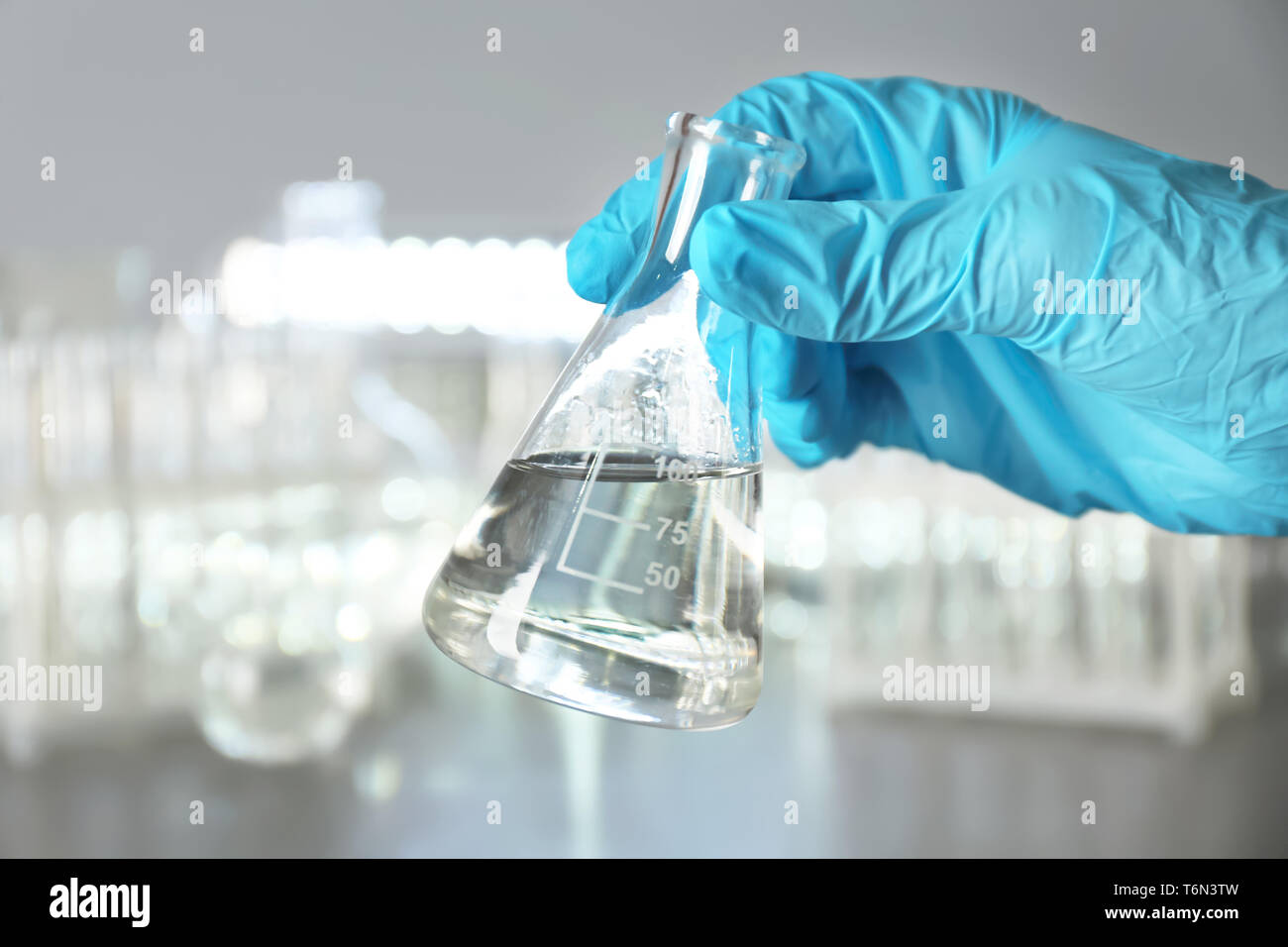 Laboratory worker holding flask with water on blurred background Stock ...