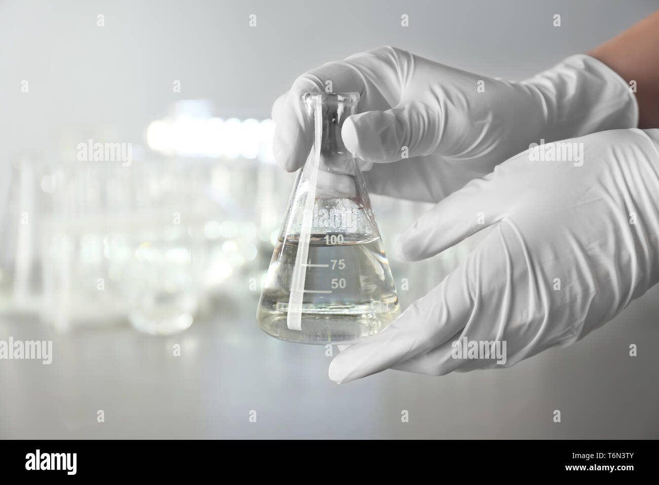 Laboratory worker holding flask with water on blurred background Stock ...