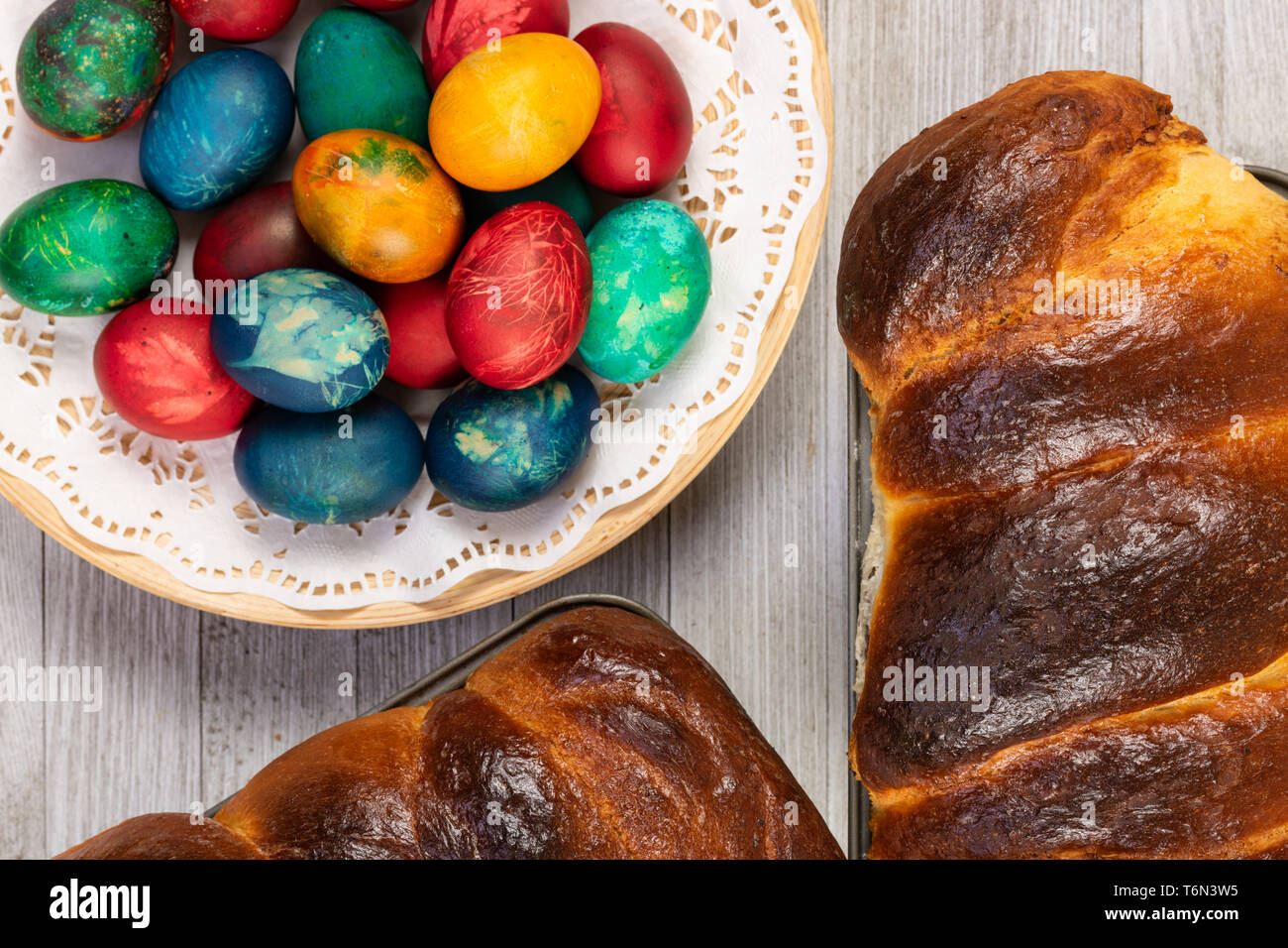 Traditional sweet bread in baking pan and Easter painted eggs, top view ...