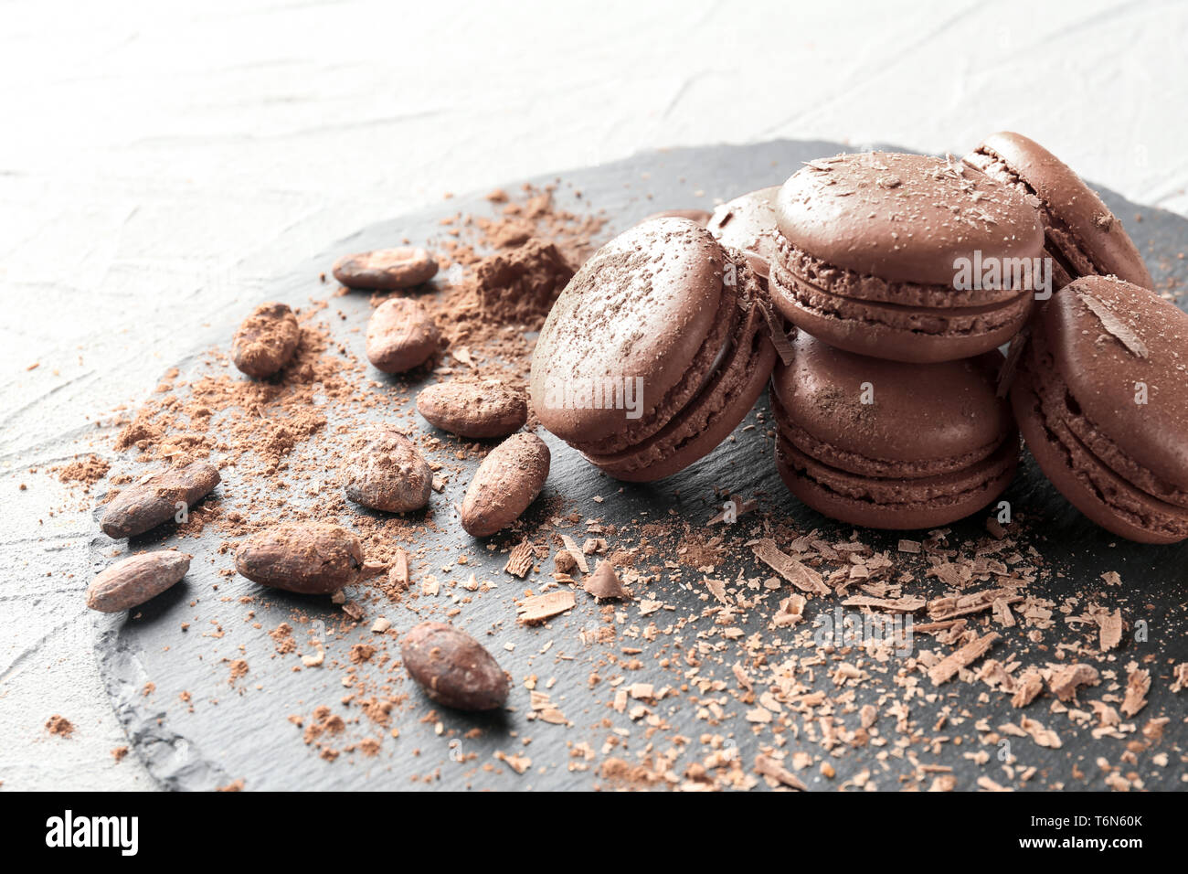 Slate plate with delicious chocolate macarons and cocoa beans on table ...