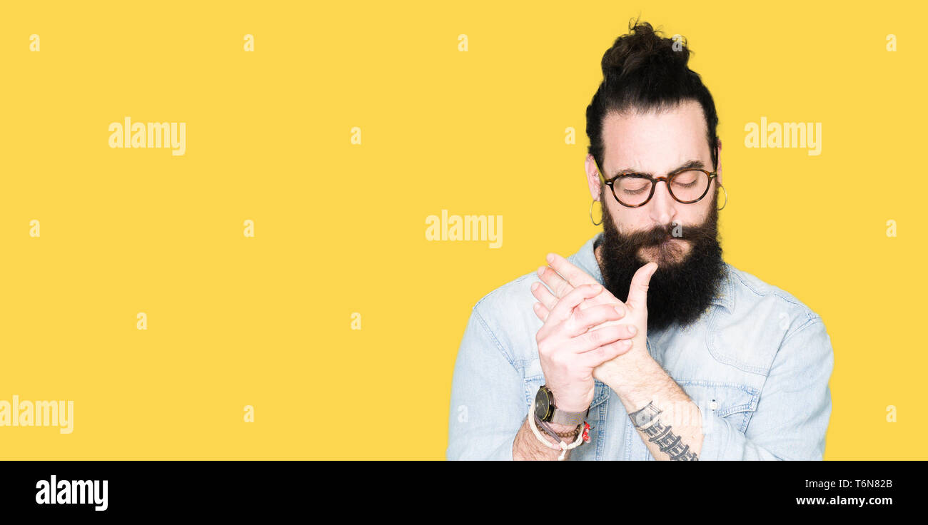 Young hipster man with long hair and beard wearing glasses Suffering ...