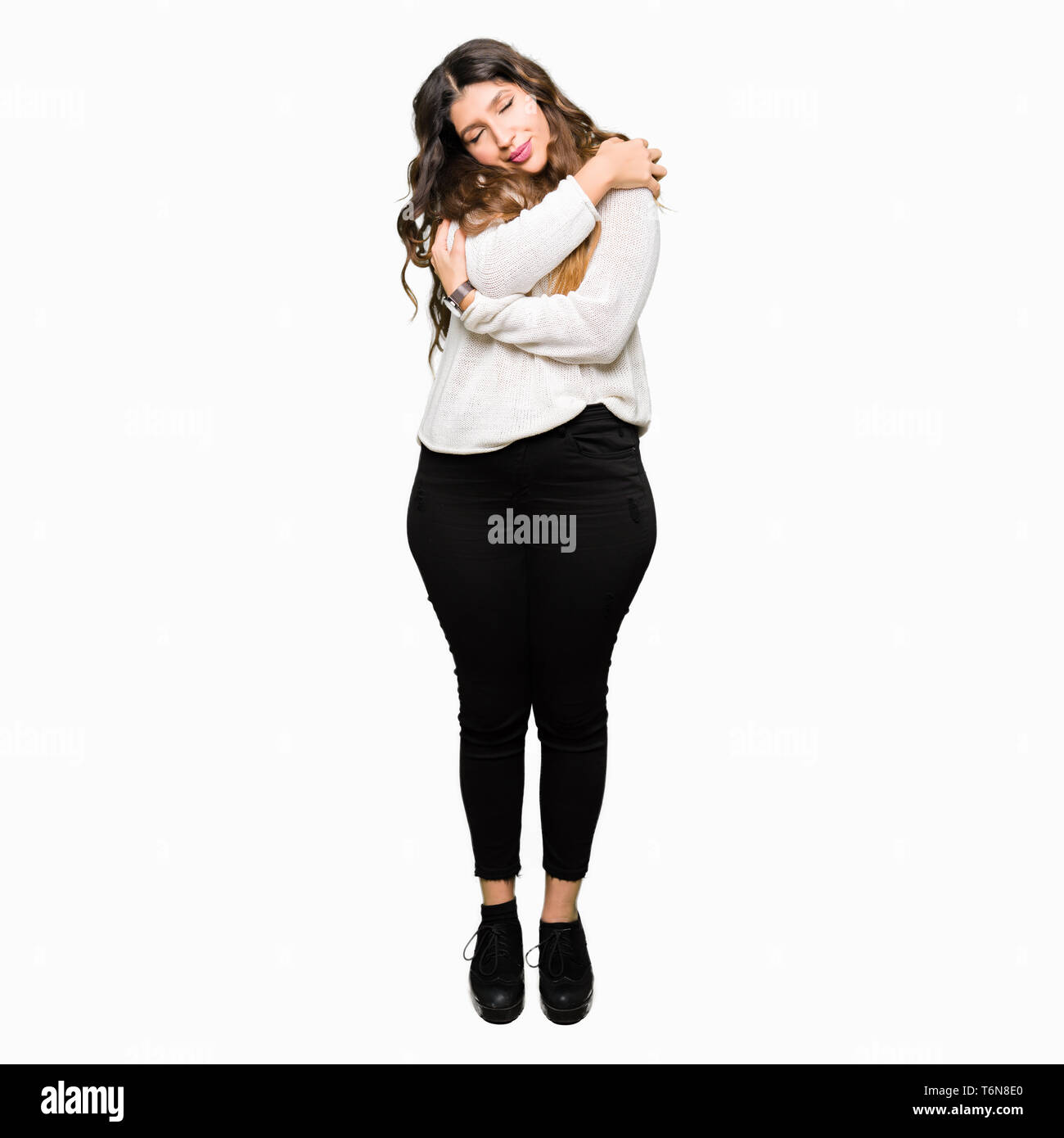 Young beautiful woman wearing white sweater Hugging oneself happy and ...